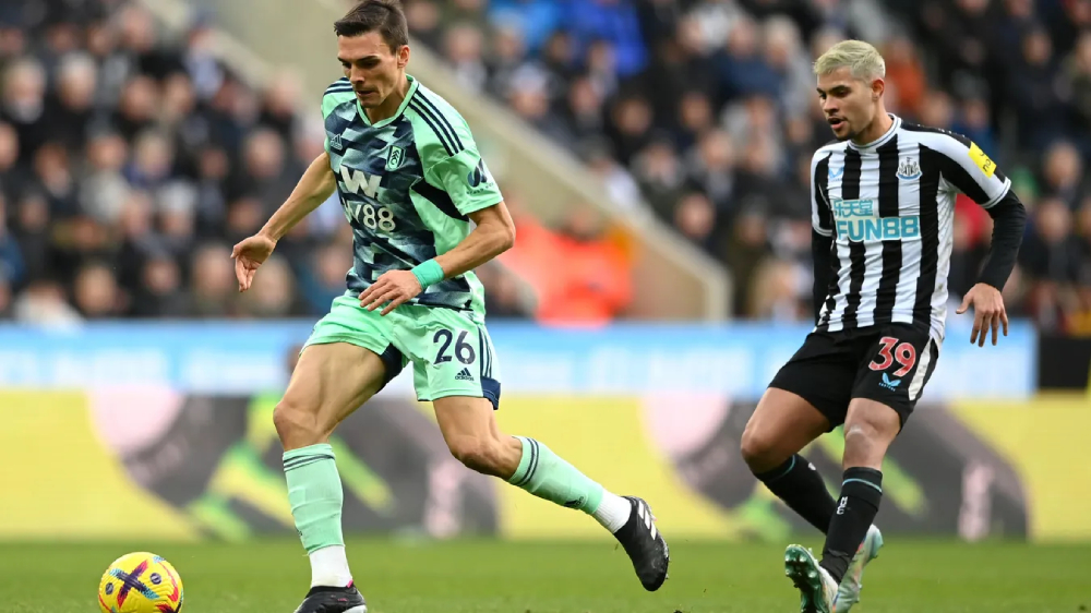 Players from Fulham (in green) and Newcastle United (in black and white ...
